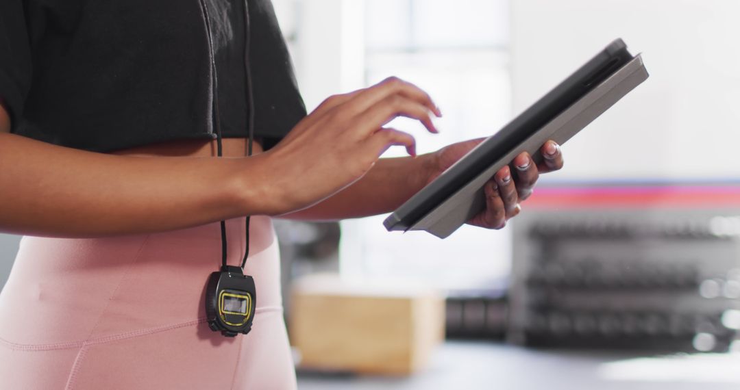 Female Fitness Trainer Using Tablet in Gym with Stopwatch