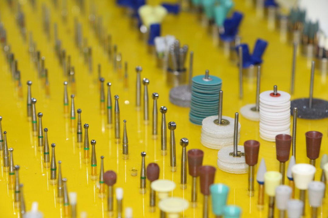 Colorful Assortment of Dental Drill Bits on Yellow Surface